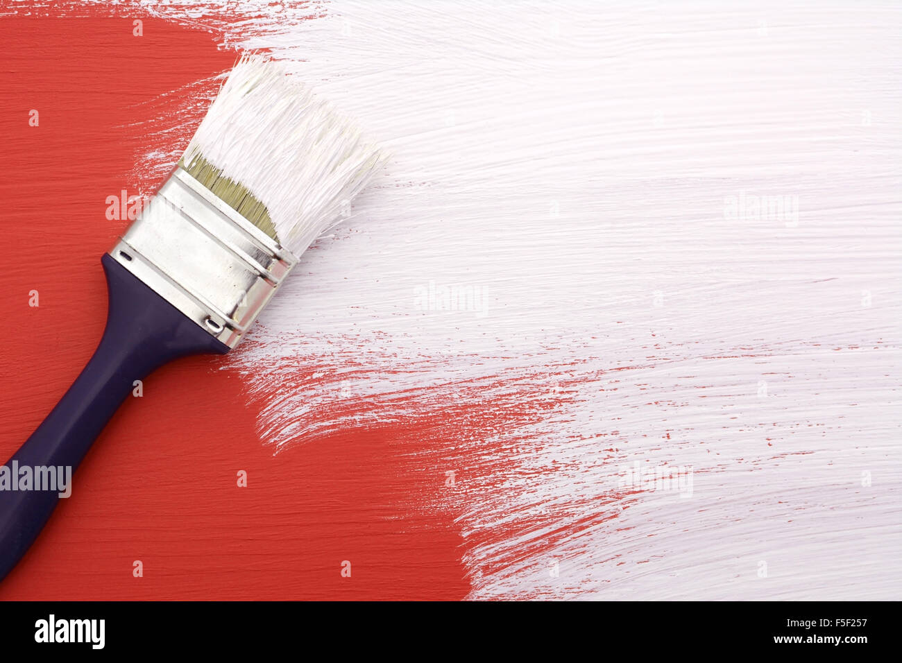 Pinsel mit weißer Farbe Malerei über die rote Farbe auf einem Kiefer ...
