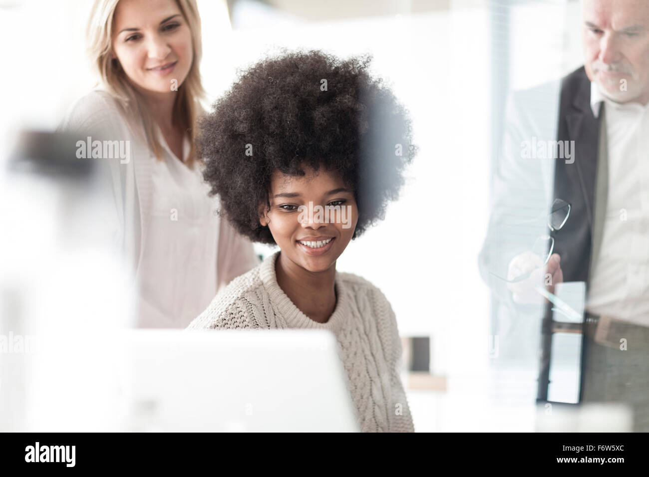 Kolleginnen und Kollegen im Büro arbeiten zusammen am laptop ...