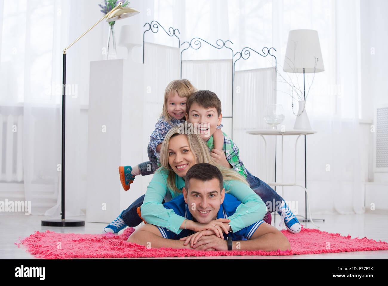 Glückliche Eltern und ihre Kinder lachen auf dem Boden in einem hellen ...