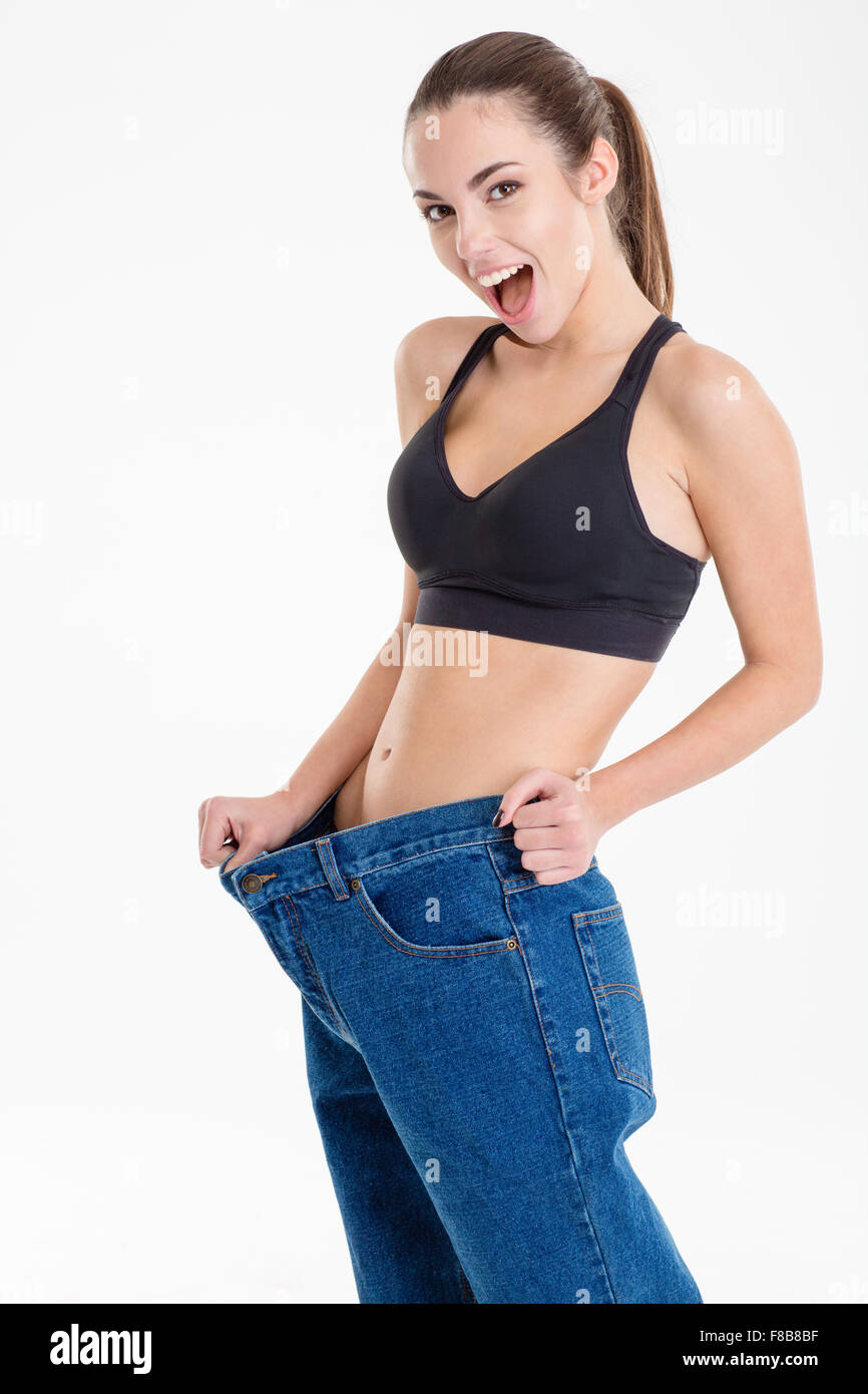 Erstaunt glückliche junge Fitness Frau wurde dünn und tragen alte Jeans ... Erstaunt glückliche junge Fitness Frau wurde dünn und tragen alte Jeans ...