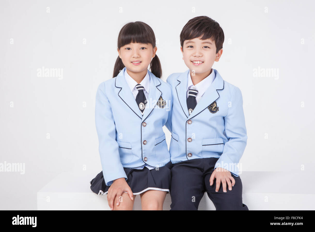 Grundschule-jungen und Mädchen in Schuluniformen sitzen zusammen mit ihrer Hand umeinander ...