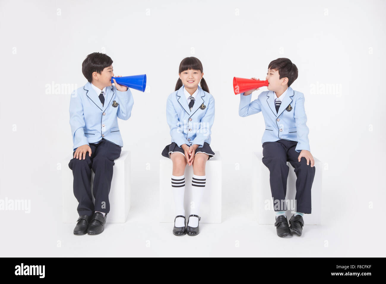 Zwei Grundschule jungen in Schuluniformen sprechen durch eine plastische Megaphon jeweils gegen ...