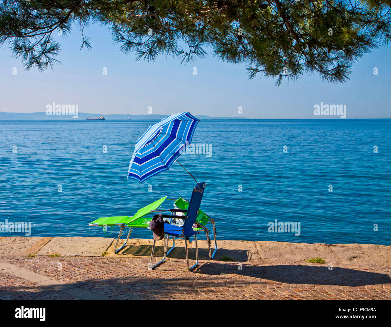 Liege mit Sonnenschirm bereit vor blauen Meerwasser am freien Strand ...