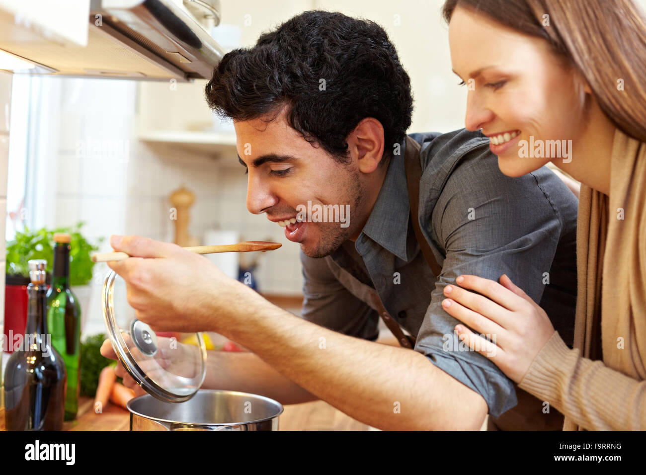 Mann, die Suppe auf dem Herd in der Küche zu probieren, während ...
