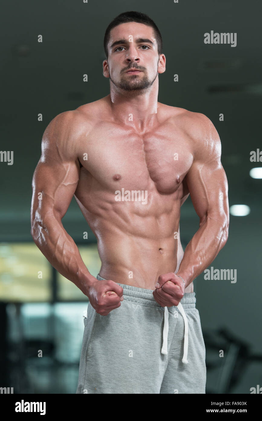 Awesome Bodybuilder zeigt seine Muskeln und posiert In der Turnhalle ...
