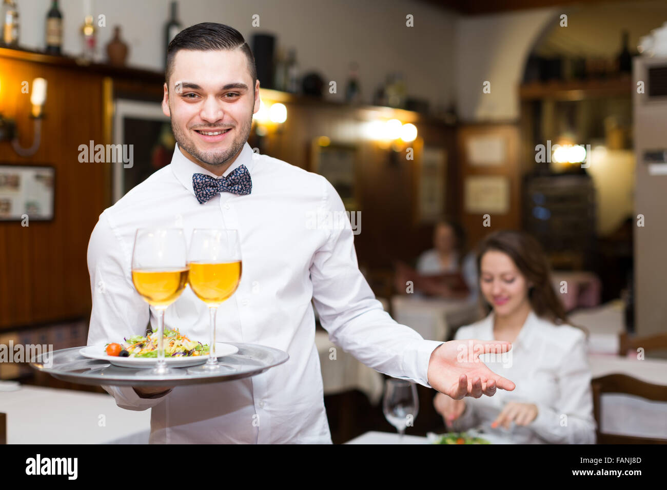 Hübscher Mann arbeitet als Kellner in einem Restaurant. Er trägt weißes ...