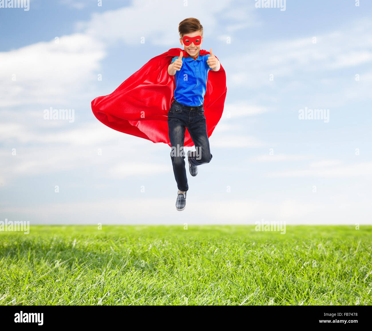 Junge in Superhelden Cape und Maske, die Daumen nach oben zeigen ...