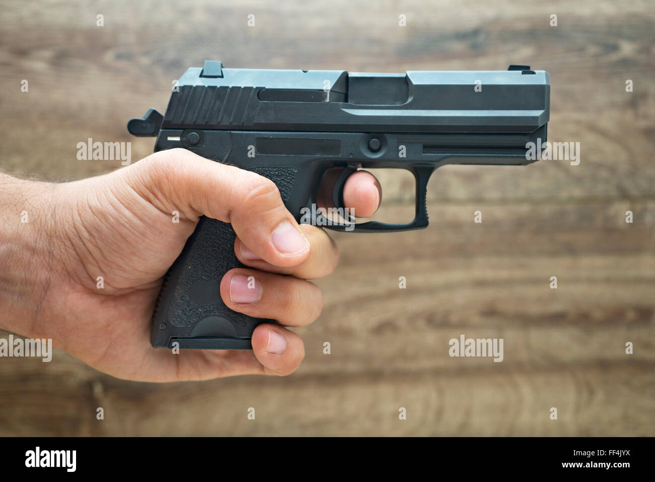 Μasculine Hand mit Pistole Pistole, Wedel aus Holz Hintergrund ...