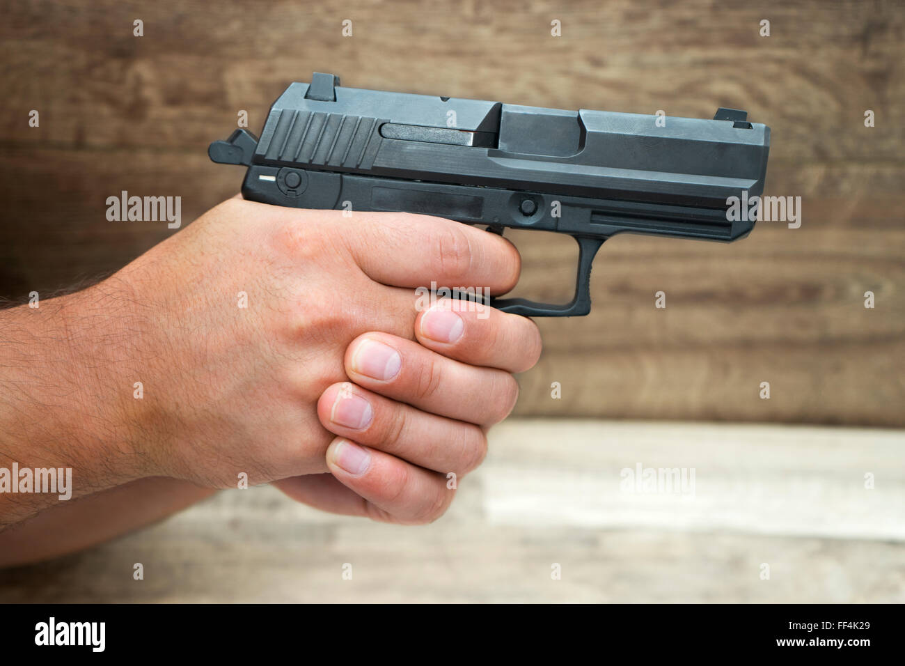Μasculine Hand mit Pistole Pistole, Wedel aus Holz Hintergrund ...