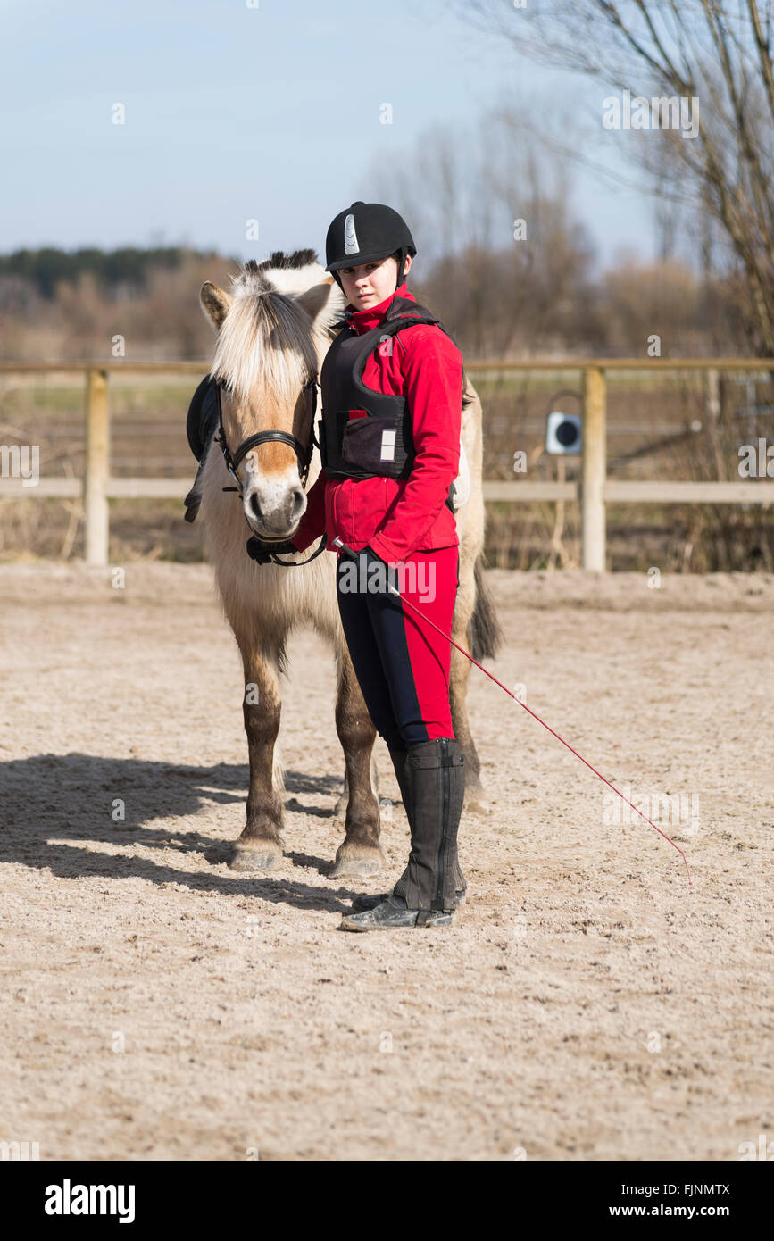 Mädchen stehen neben einem Fjord-Pferd in der Reithalle und halten das ...