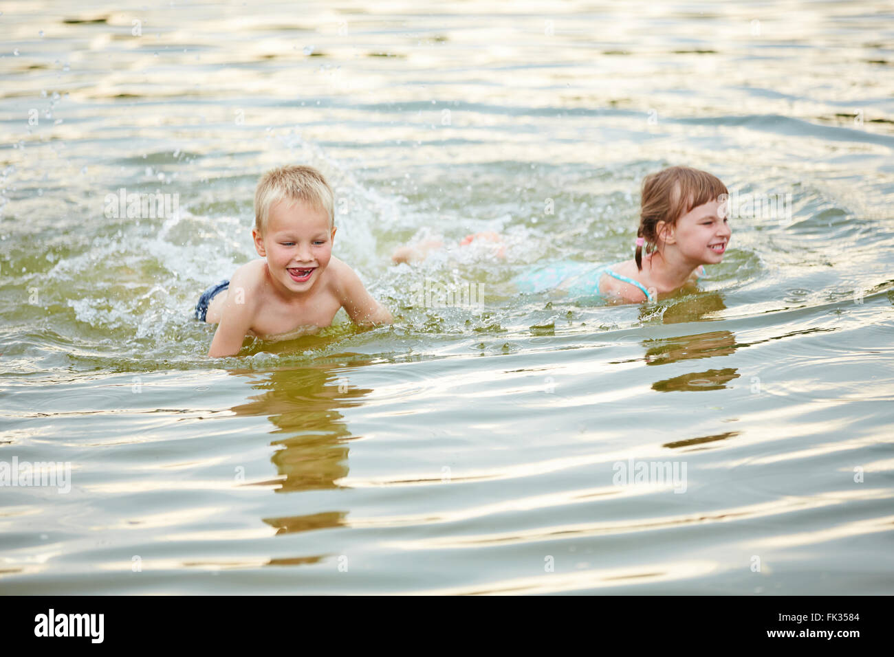 Zwei glückliche Kinder, die zusammen im Wasser des Meeres im Sommer ...
