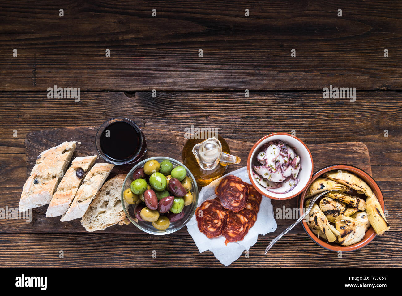 Holzbrett mit Tapas, Oliven und Salami und Oliven-Öl, von oben ...