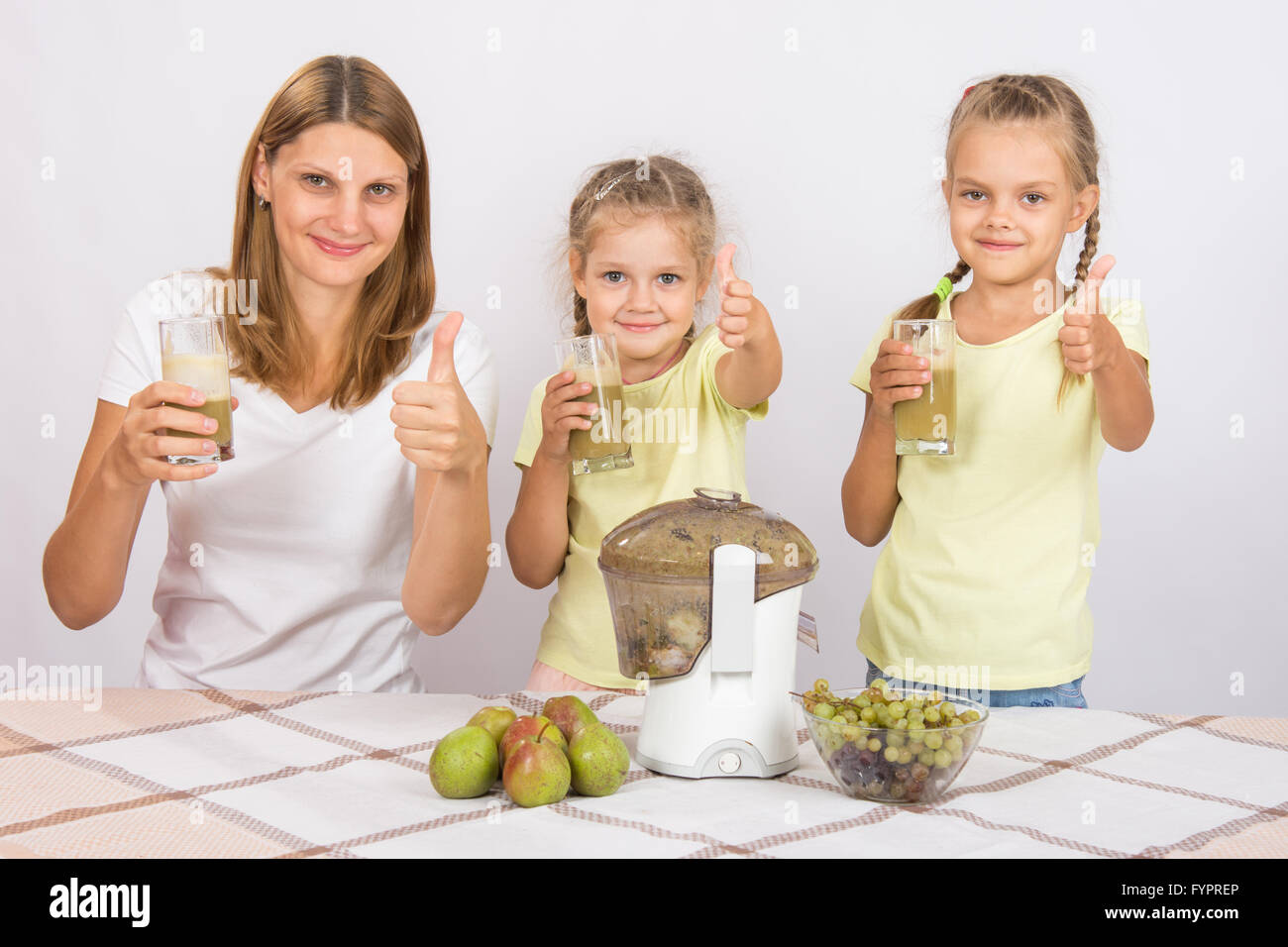 Mutter und zwei Töchter zeigen ein Daumen hoch frisch zubereitete Saft ...