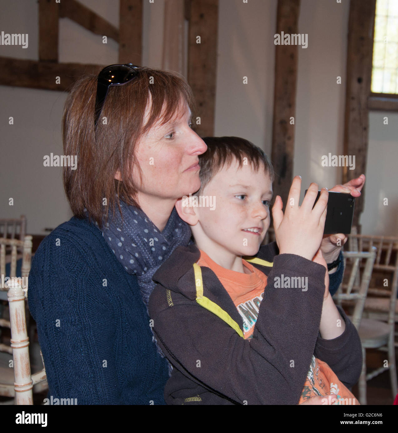 Junge sitzt auf Mutters Schoß Blick auf Handy Stockfotografie - Alamy