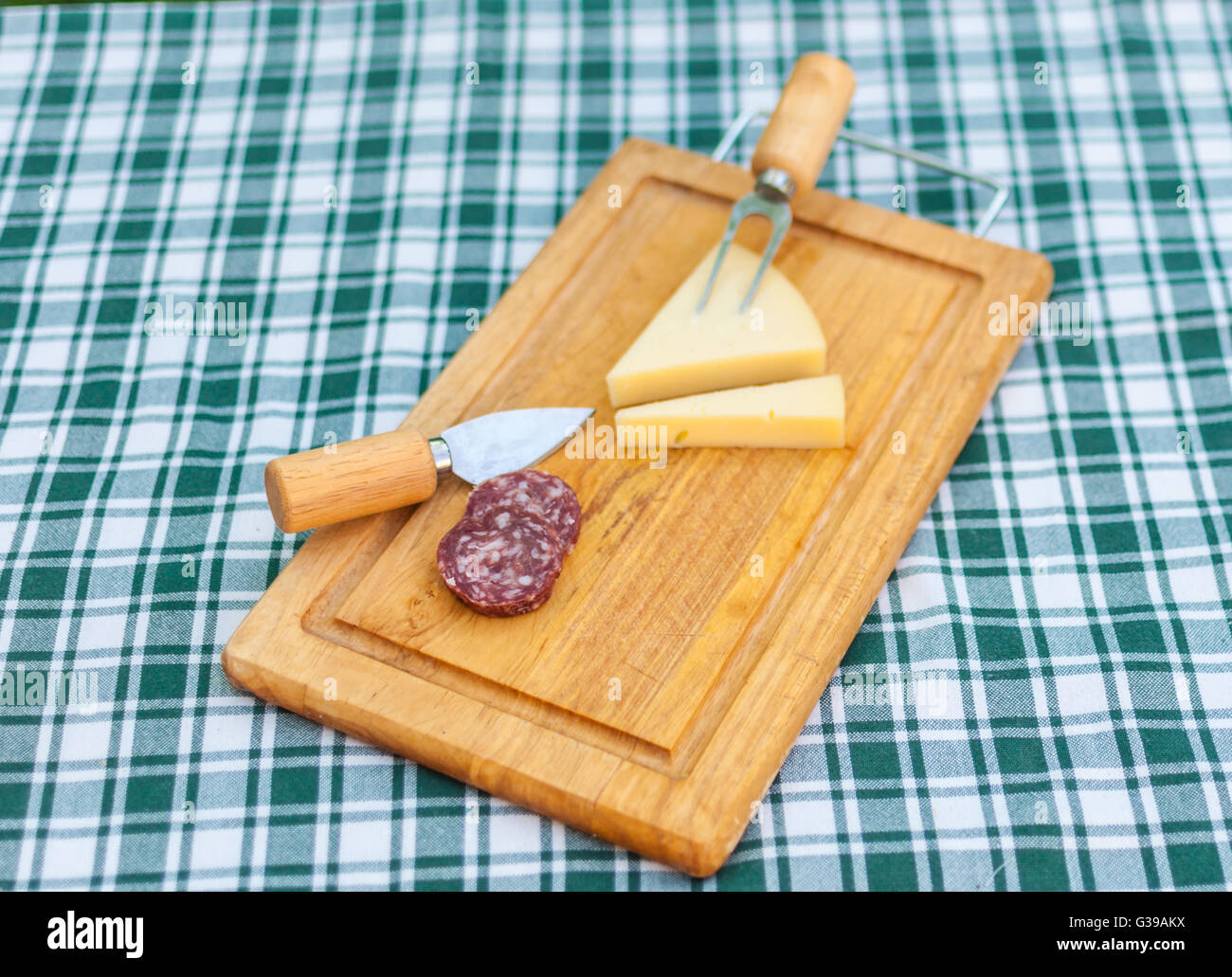 Wurst und Käse auf ein Schneidbrett aus Holz draußen im Sommer ...