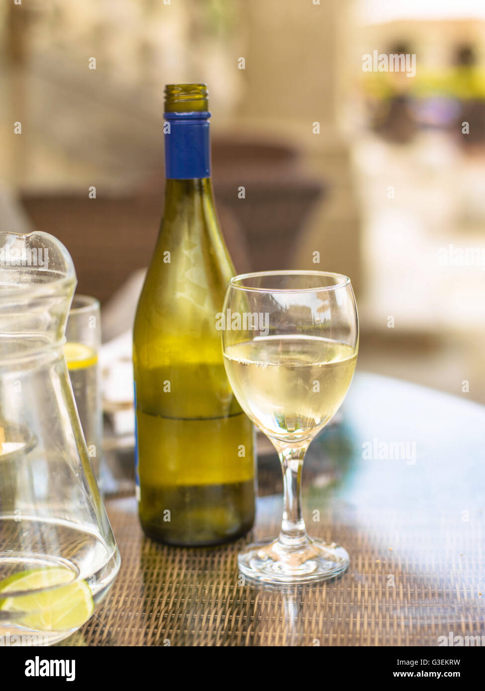Flasche halb leer Weißwein auf einem geflochtenen Tisch mit Glas und ...
