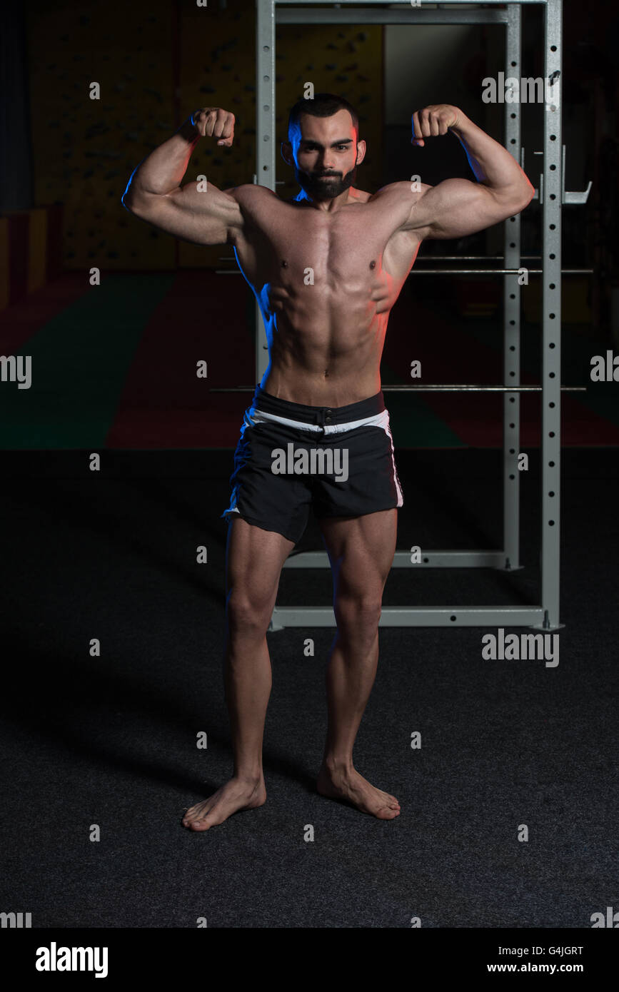 Junger Mann standhaft In der Turnhalle und Durchführung vordere Doppel ...