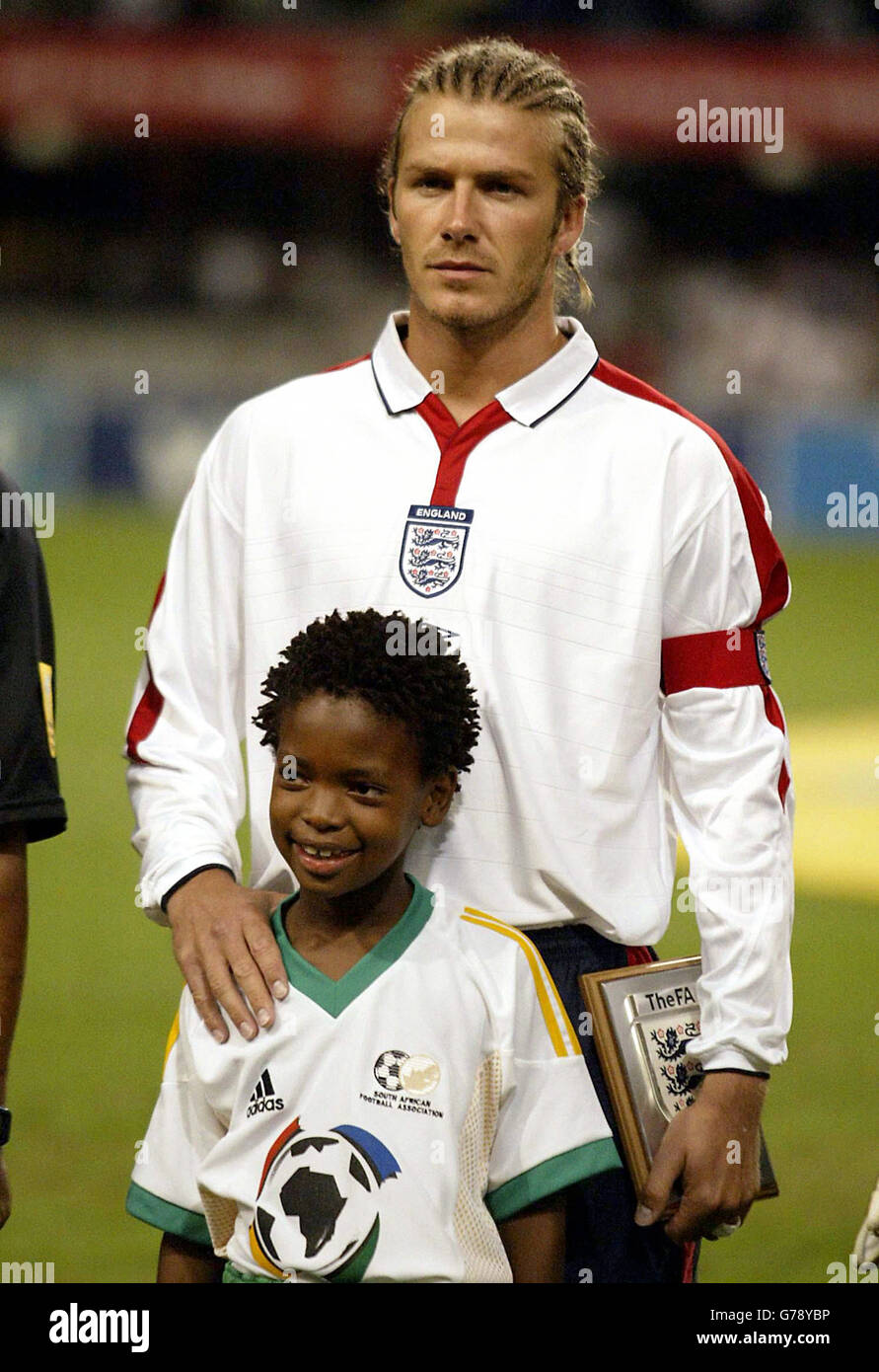 Englands Fußball-Nebenmann David Beckham steht mit dem südafrikanischen Kind vor seinem ...