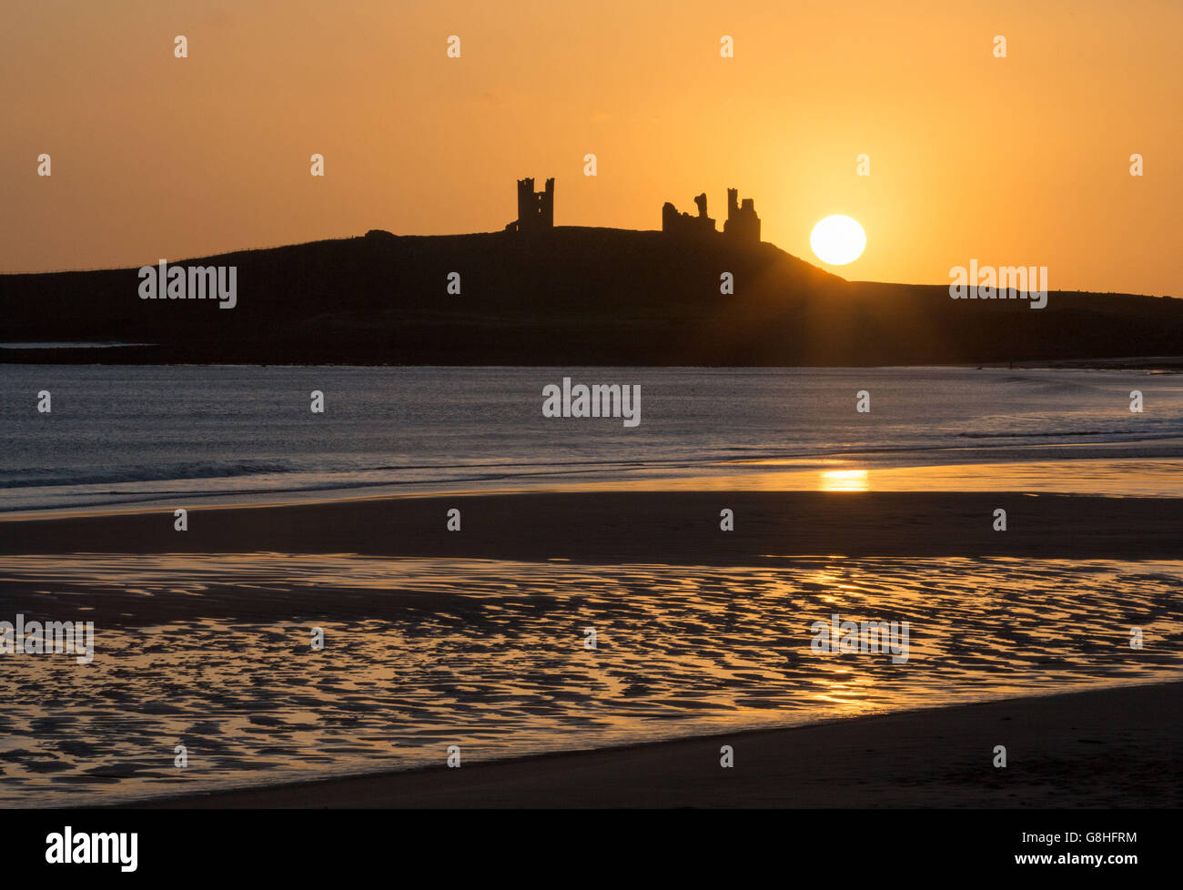 Die Sonne geht über Dunstanburgh Castle, Embleton Bay in Northumberland ...