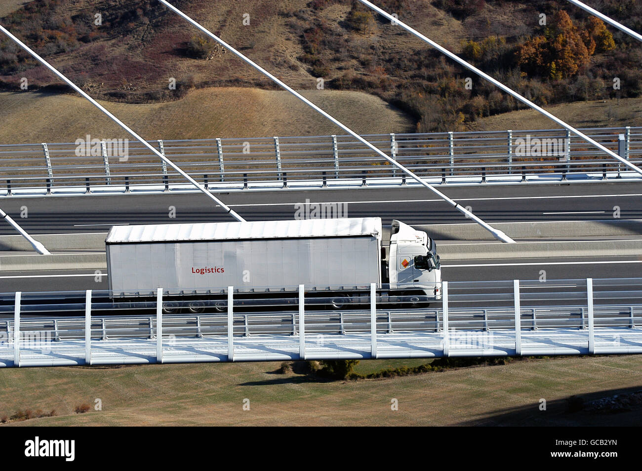 LKW auf der Autobahn unterwegs und vorbei an einem hohen Viadukt die ...