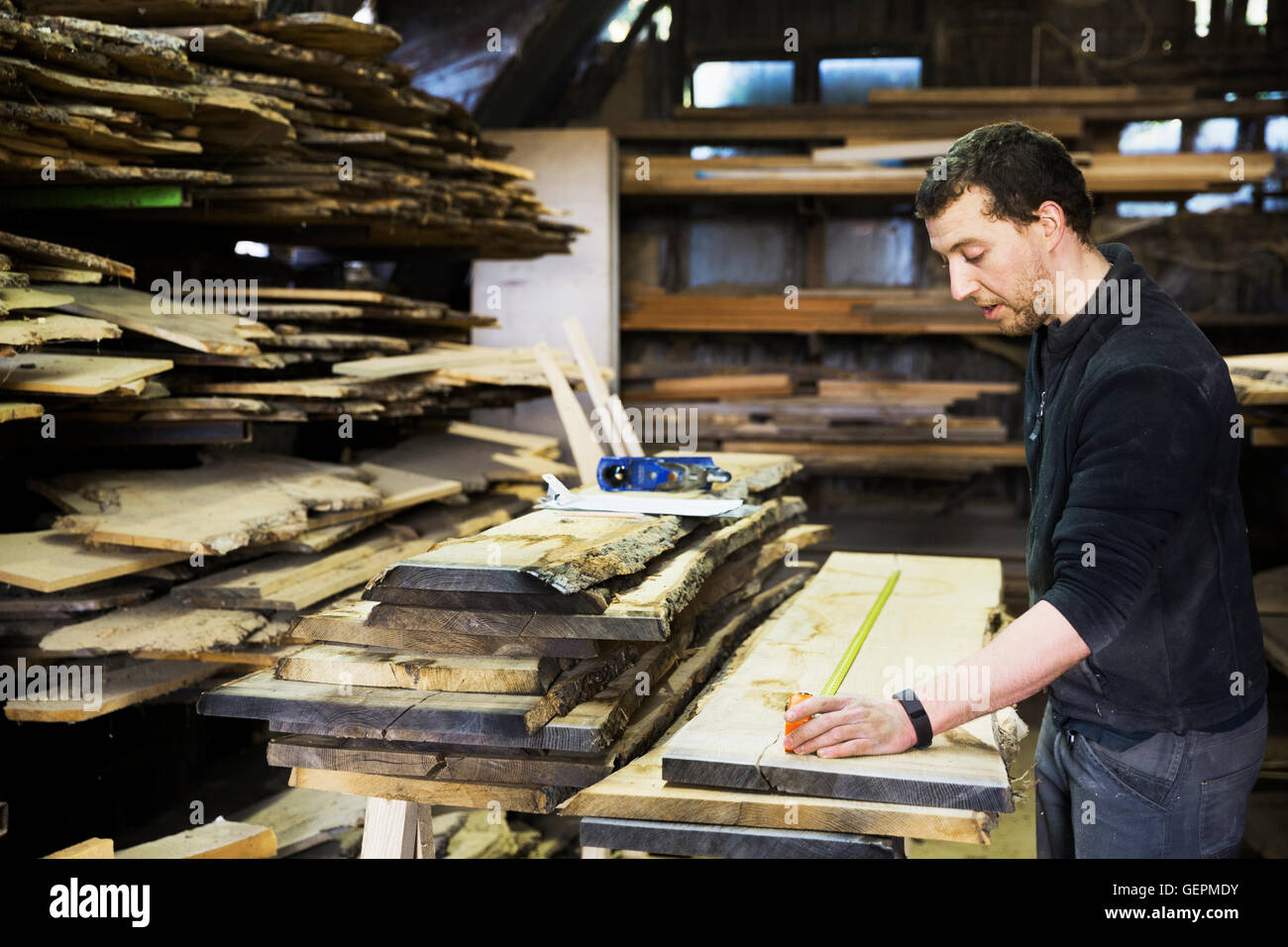 Mann arbeitet in einer Tischlerei, ein Stück Holz zu messen ...