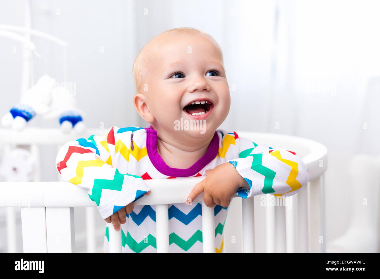 Süße lachende Baby stehend im Bett nach der Ruhezeit. Kindergarten ...