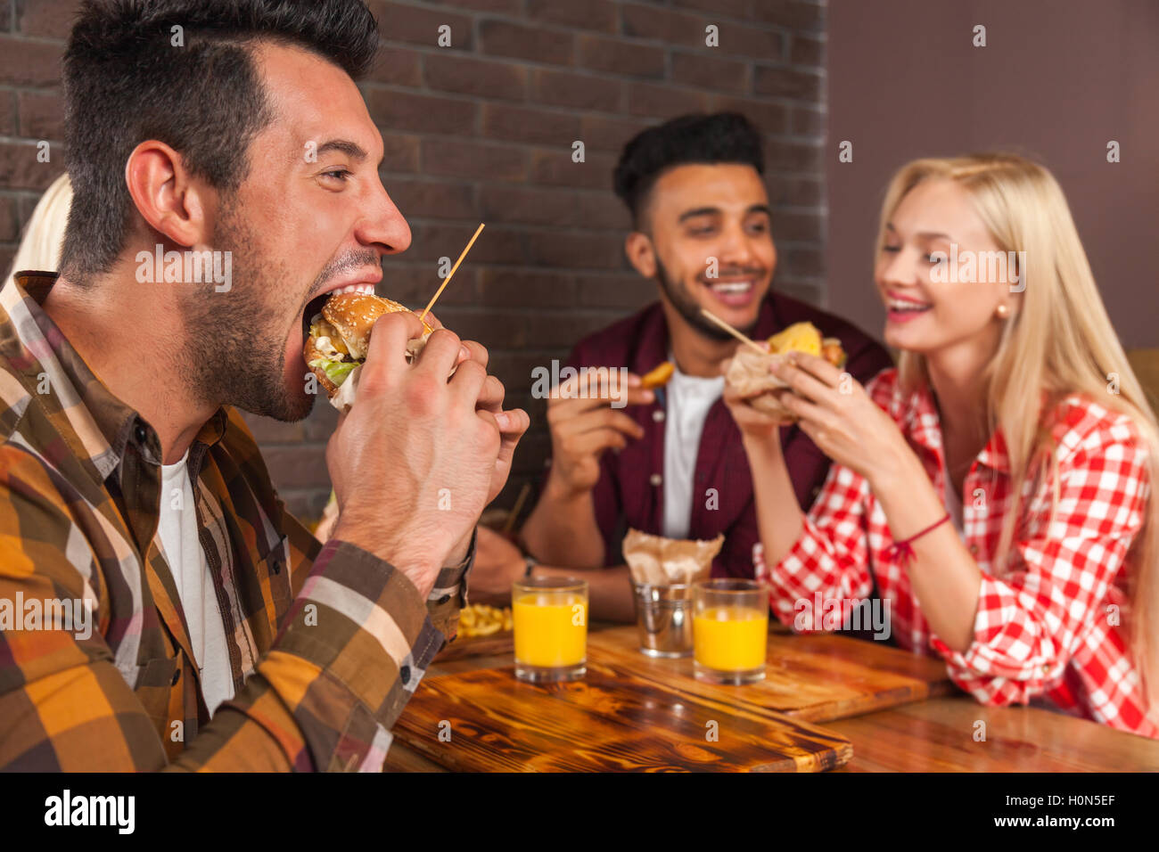Personen Gruppe Essen Fast-Food-Burger am Holztisch im Cafe sitzen ...