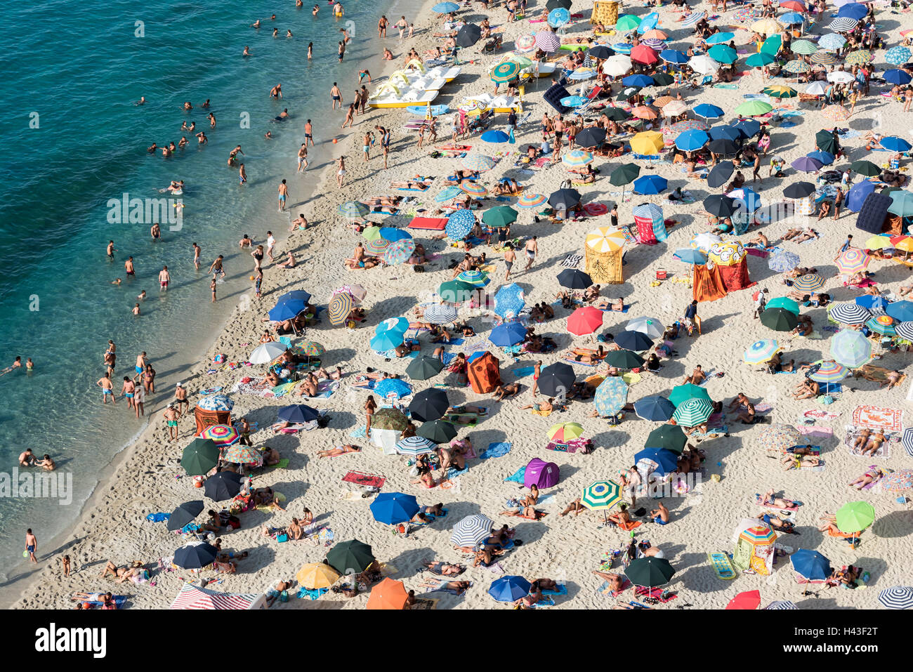 Viele Menschen mit bunten Sonnenschirmen am Strand von Tropea ...