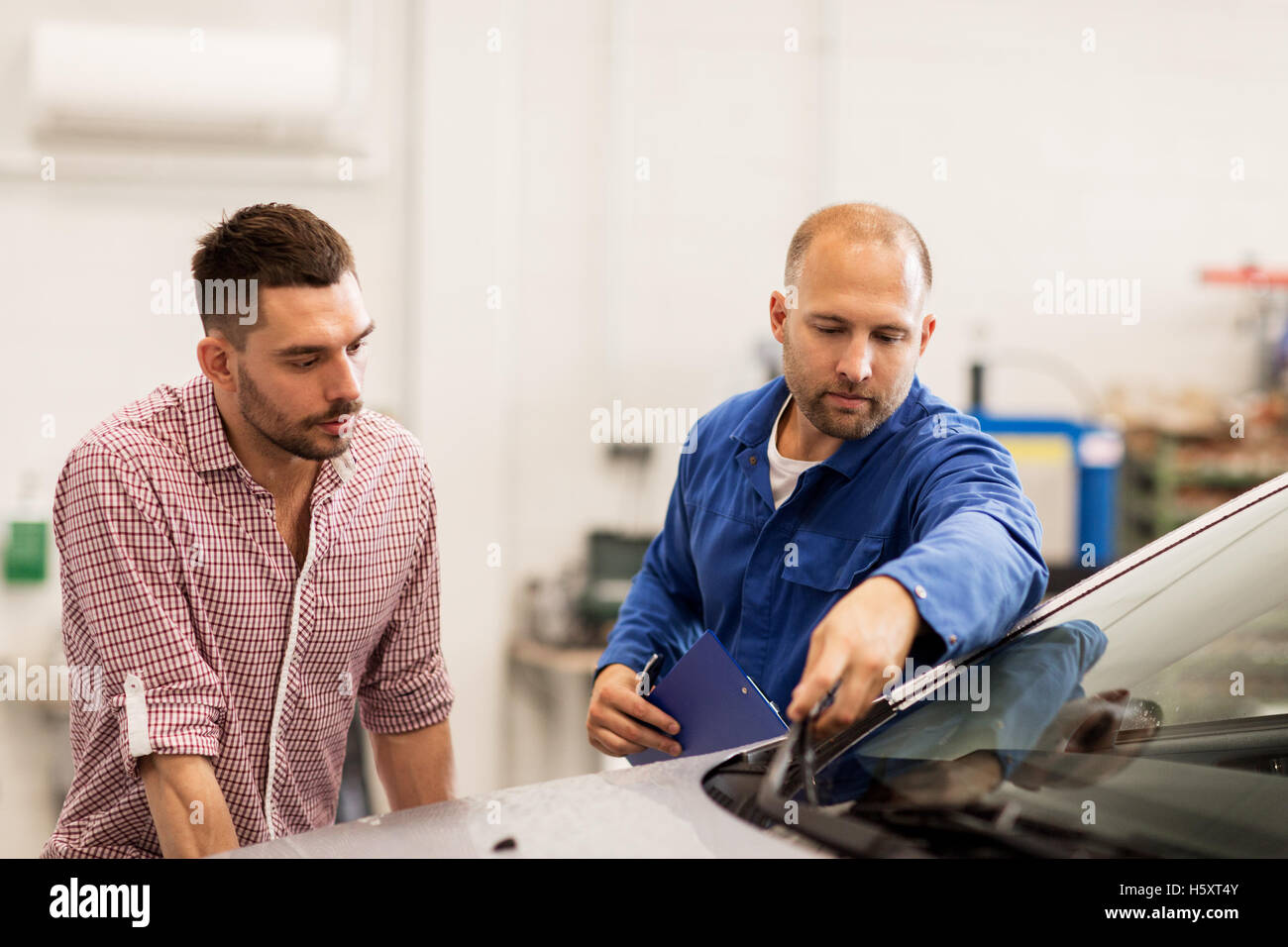 Automechaniker mit Zwischenablage und Mann an dem Auto Shop ...