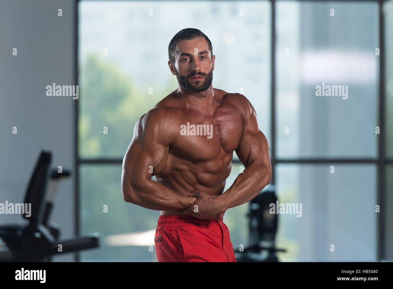 Junge Italiener stehen stark In der Turnhalle und beugen Muskeln ...