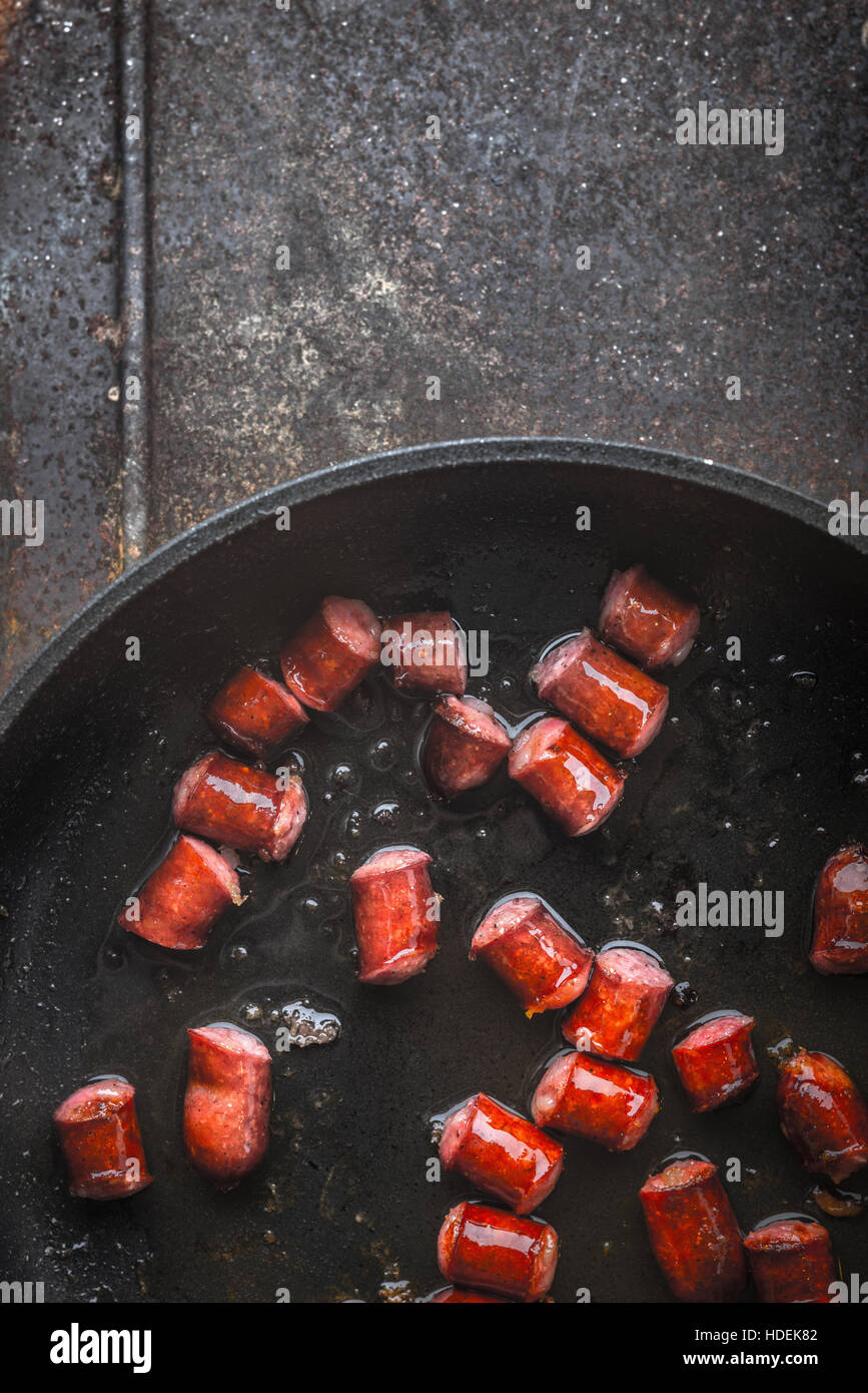 Gebratene geräucherte Wurst in der Pfanne auf dem Metall Hintergrund ...
