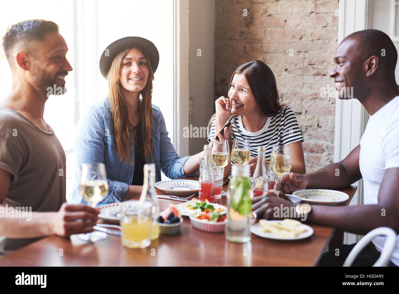 Gruppe von vier junge Leute sitzen am Tisch essen und aktive Gespräch ...