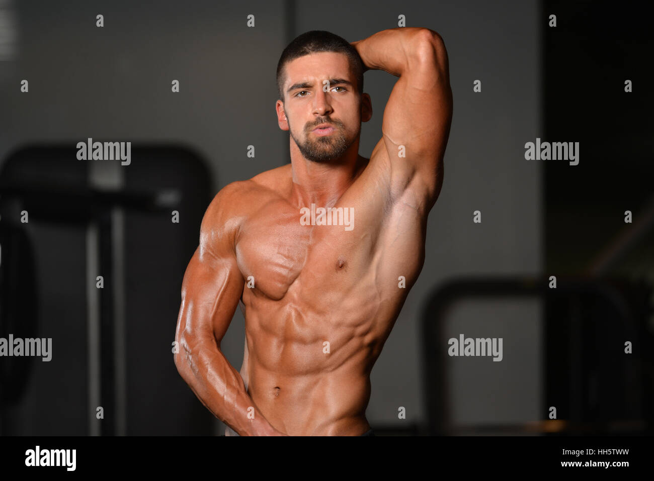 Hübscher junger Mann standhaft In der Turnhalle und biegen Muskeln ...