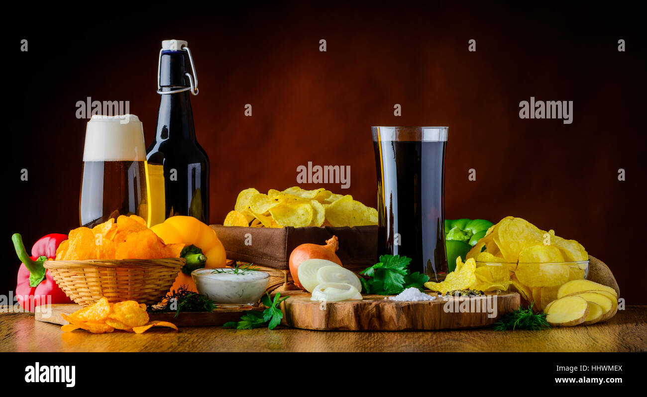Bier, Cola und Kartoffel-Chips und Zutaten in Stillleben ...
