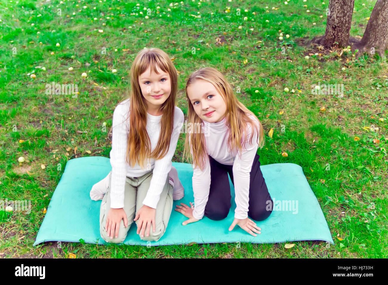 Foto von zwei Mädchen sitzen auf dem Rasen im Sommer Stockfotografie ...