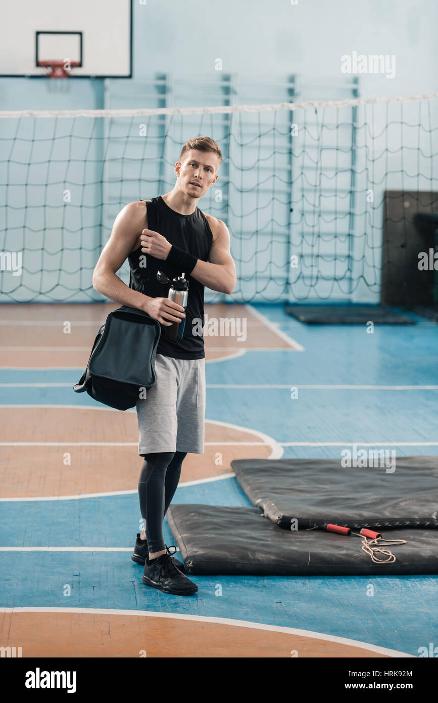 Sportlicher junger Mann mit Flasche und Tasche Blick in die Kamera in ...