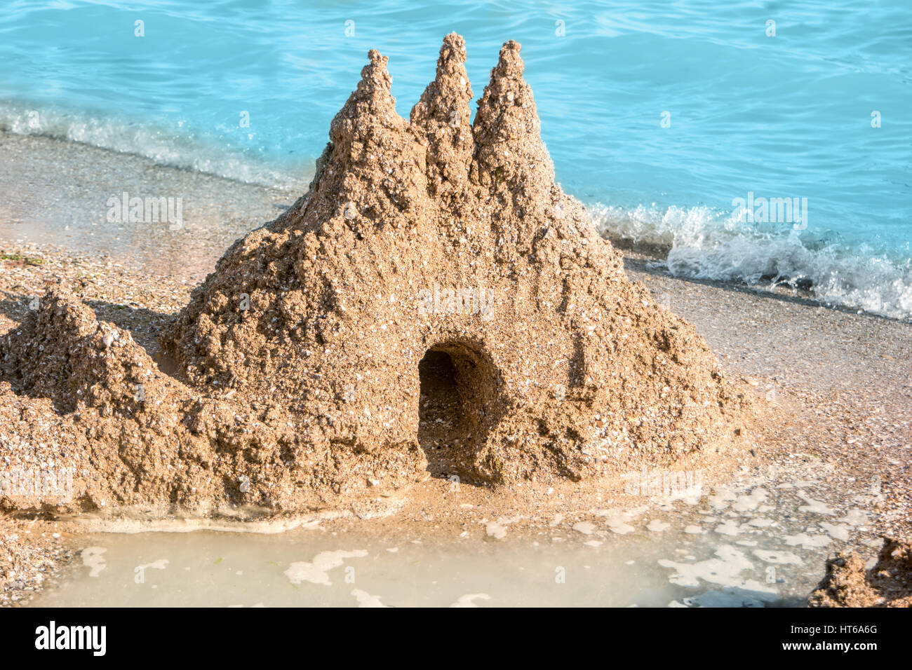 Sandburg am Strand. Sand und blaues Wasser. Kunst ist zerbrechlich ...