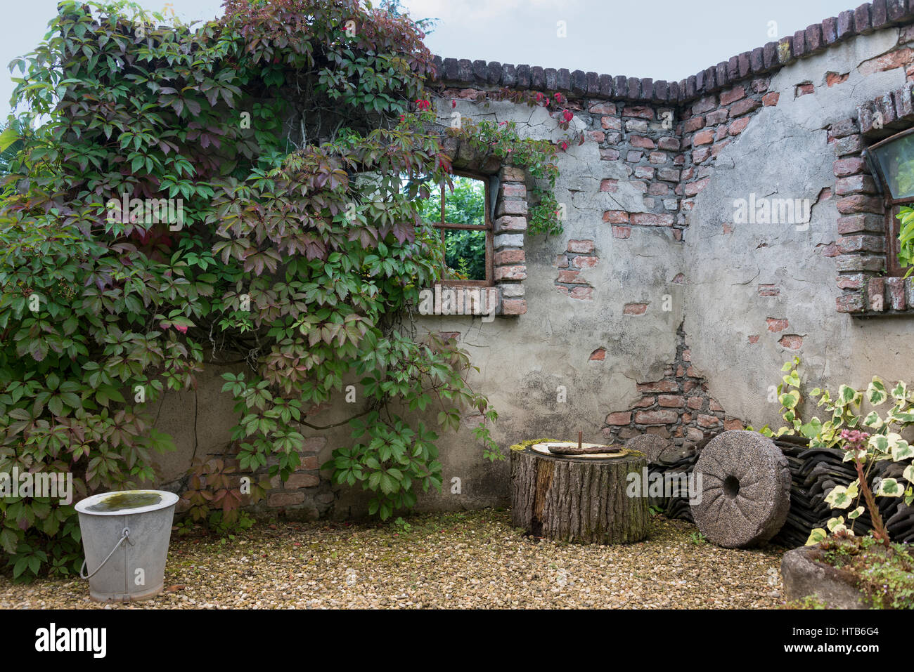 alte Mauer im Garten mit Vintage-Materialien und Pflanzen und Blumen ...