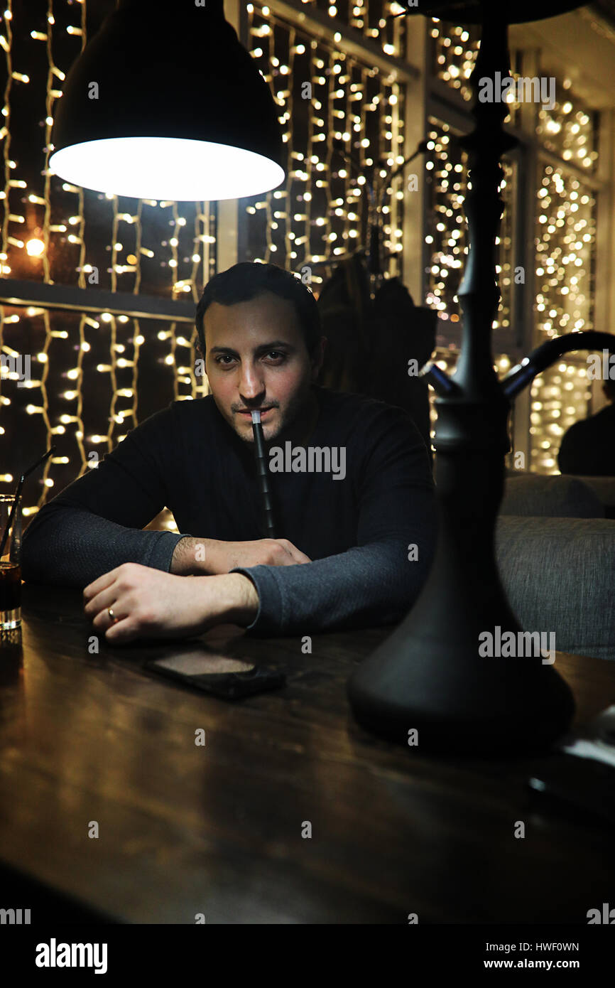 Mann hält Shisha Pfeife und Rauchen in einem Nachtclub Stockfotografie ...