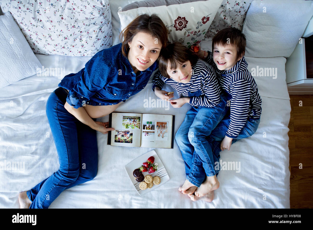Schöne Mutter und zwei Kindern, jungen, liegend auf dem Bett, Essen ...