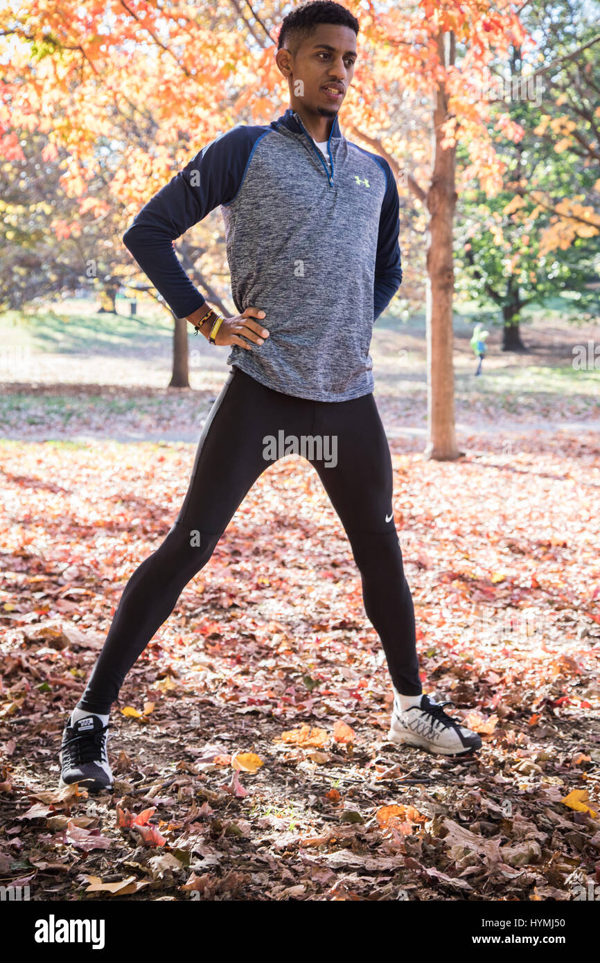 Ein junger, sportlicher Mann erstreckt sich im Park vor einem Lauf ...