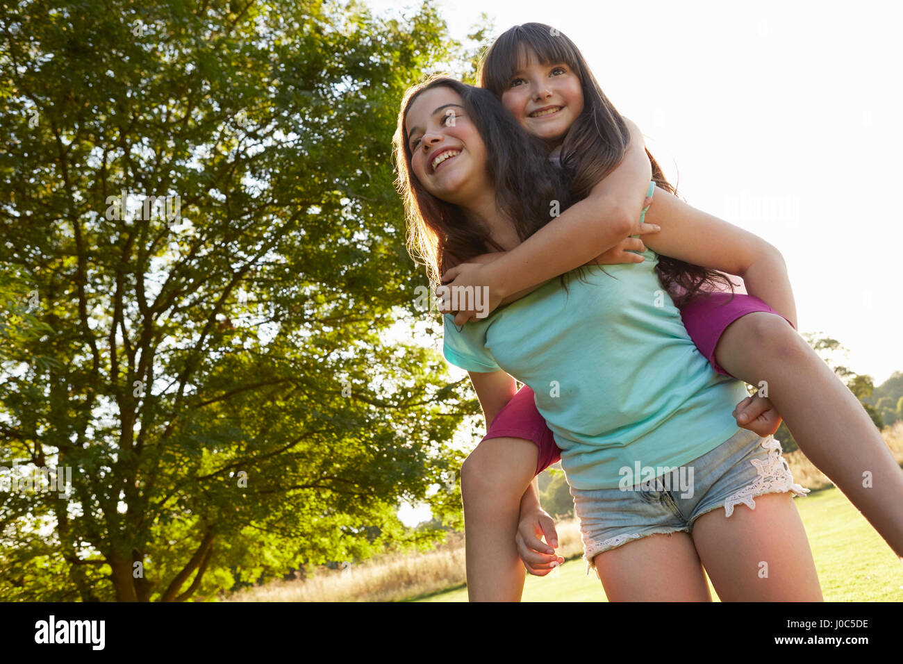 Mädchen, das ihre beste Freundin eine Huckepack im park Stockfotografie ...