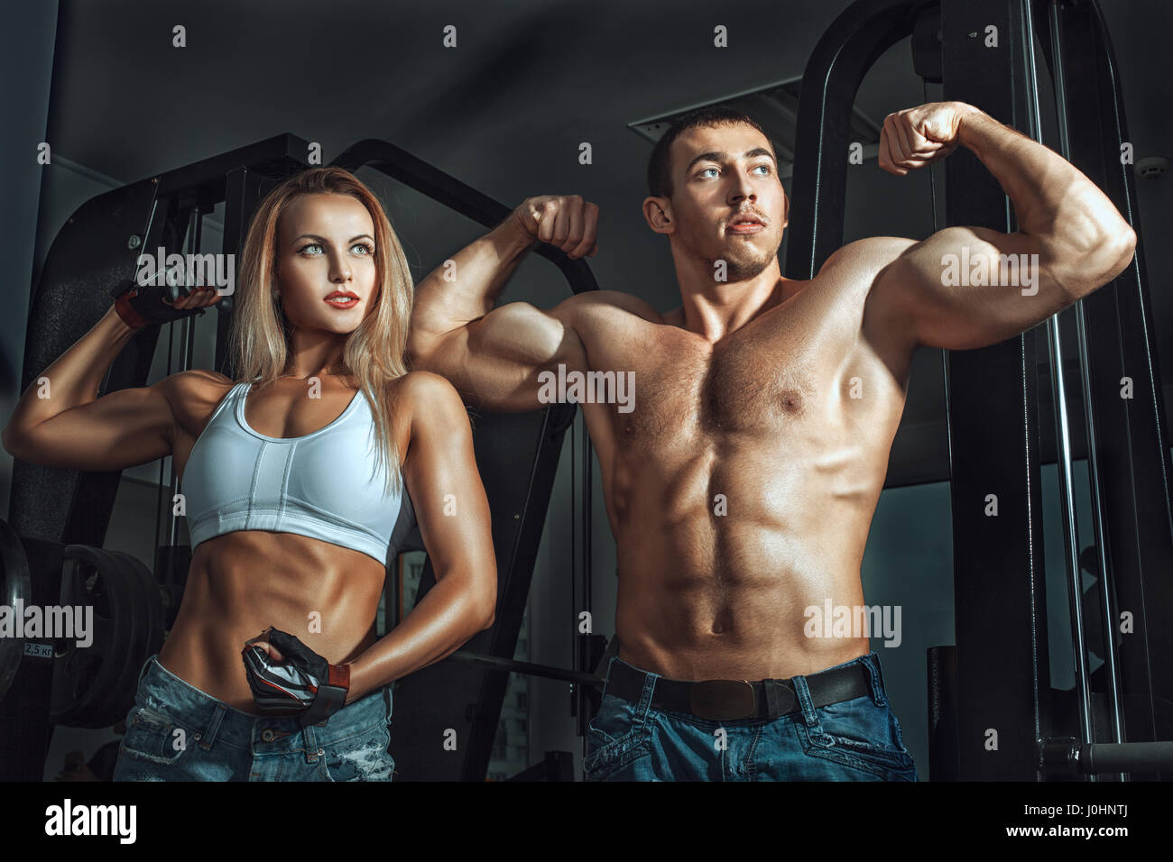 Sport-Mann und Frau im Fitnessraum und zeigen ihre Muskeln ...