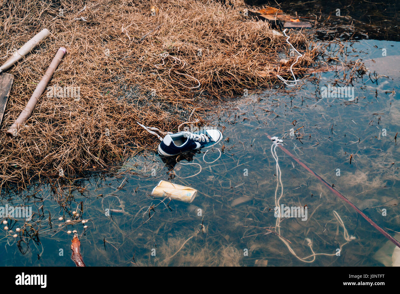 Verschmutzter Strand. Turnschuhe Schwimmen im Fluss. Müll am Ufer ...