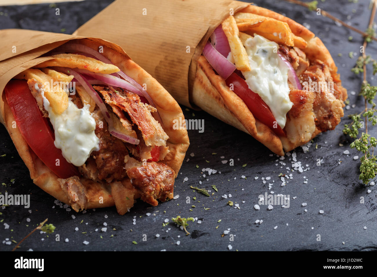 Griechische Gyros in Pita Brot auf einem schwarzen Teller gewickelt ...