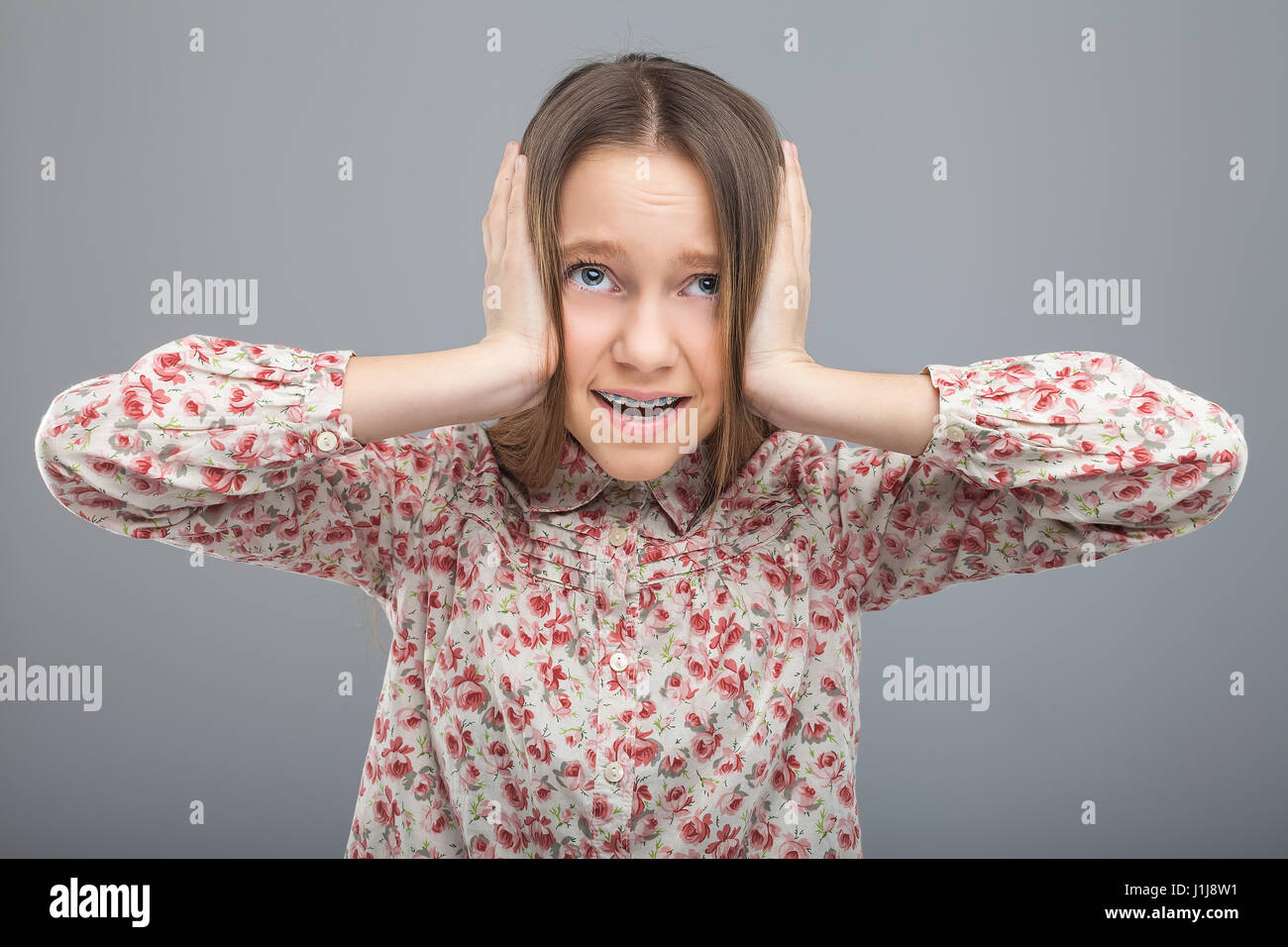 Zu laut. Young pretty Teen im Blumenkleid schließt ihre Ohren mit ...