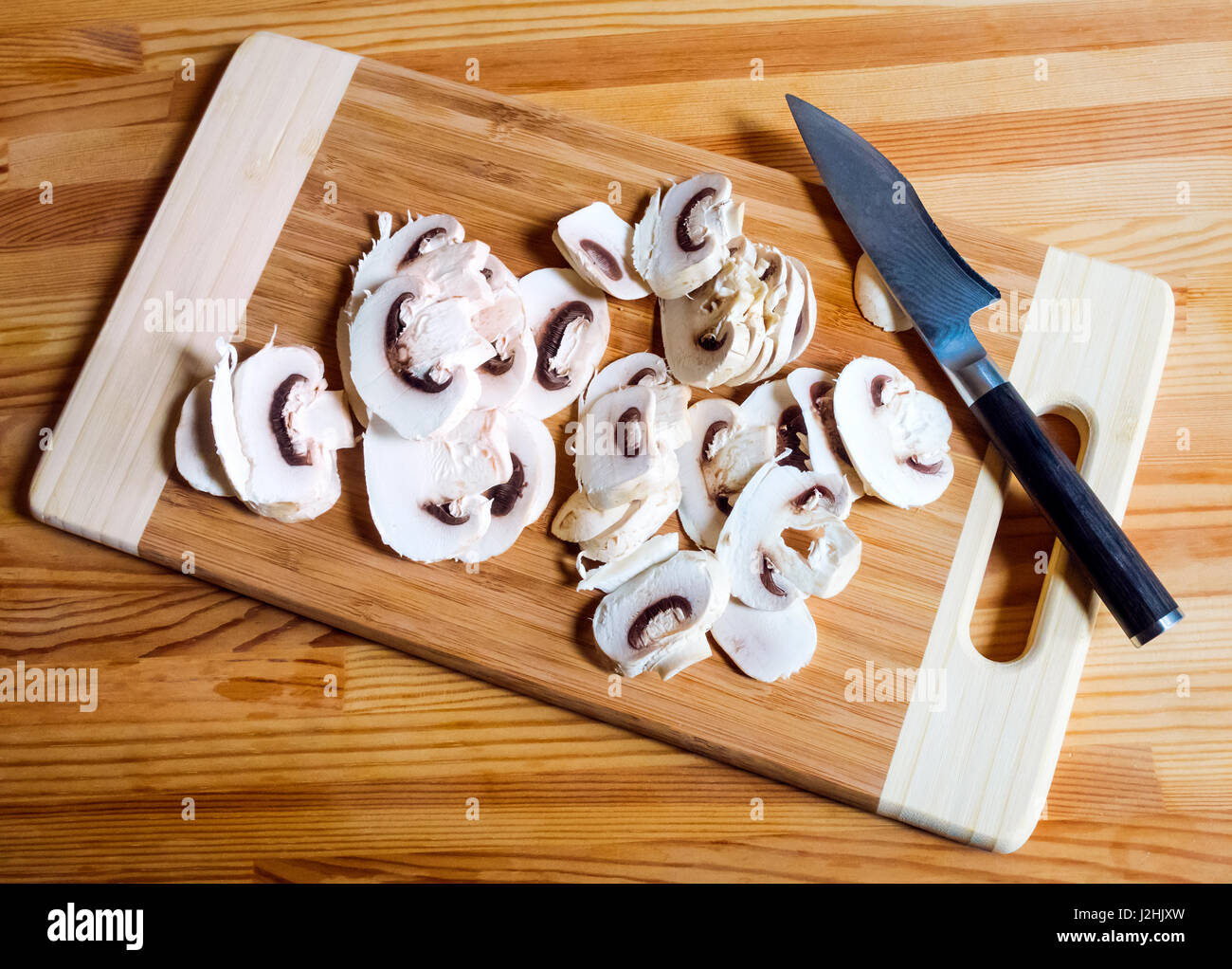 In Scheiben geschnitten Weiße Champignons auf ein Holzbrett und ein ...
