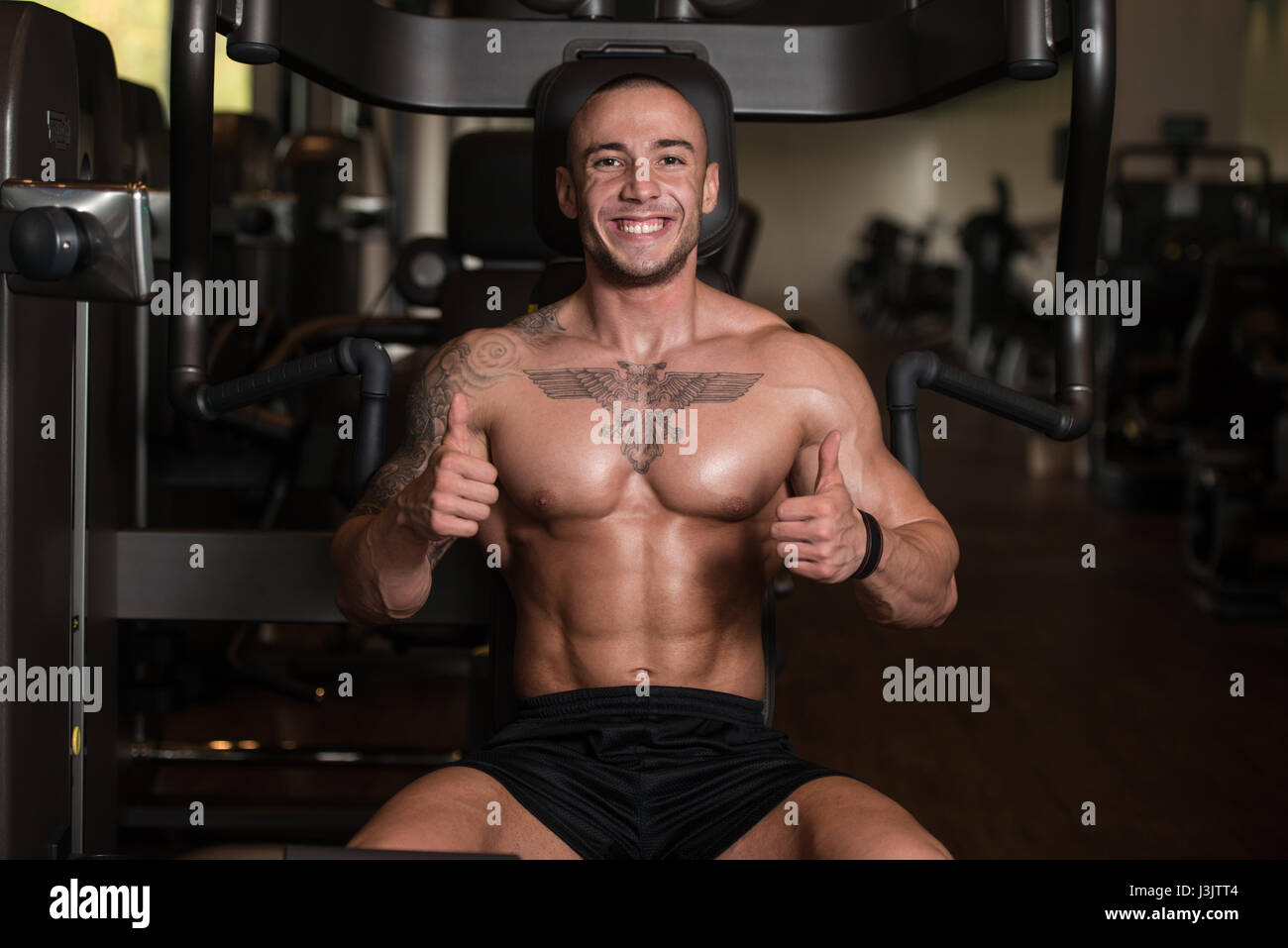 Muskulöser Mann zeigt Daumen oben beim stehen stark In ein Fitness ...