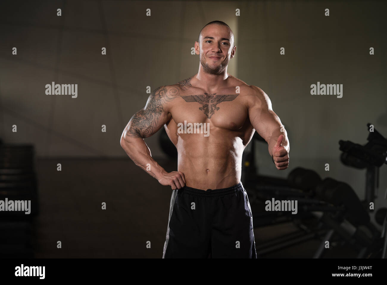 Muskulöser Mann zeigt Daumen oben beim stehen stark In ein Fitness ...