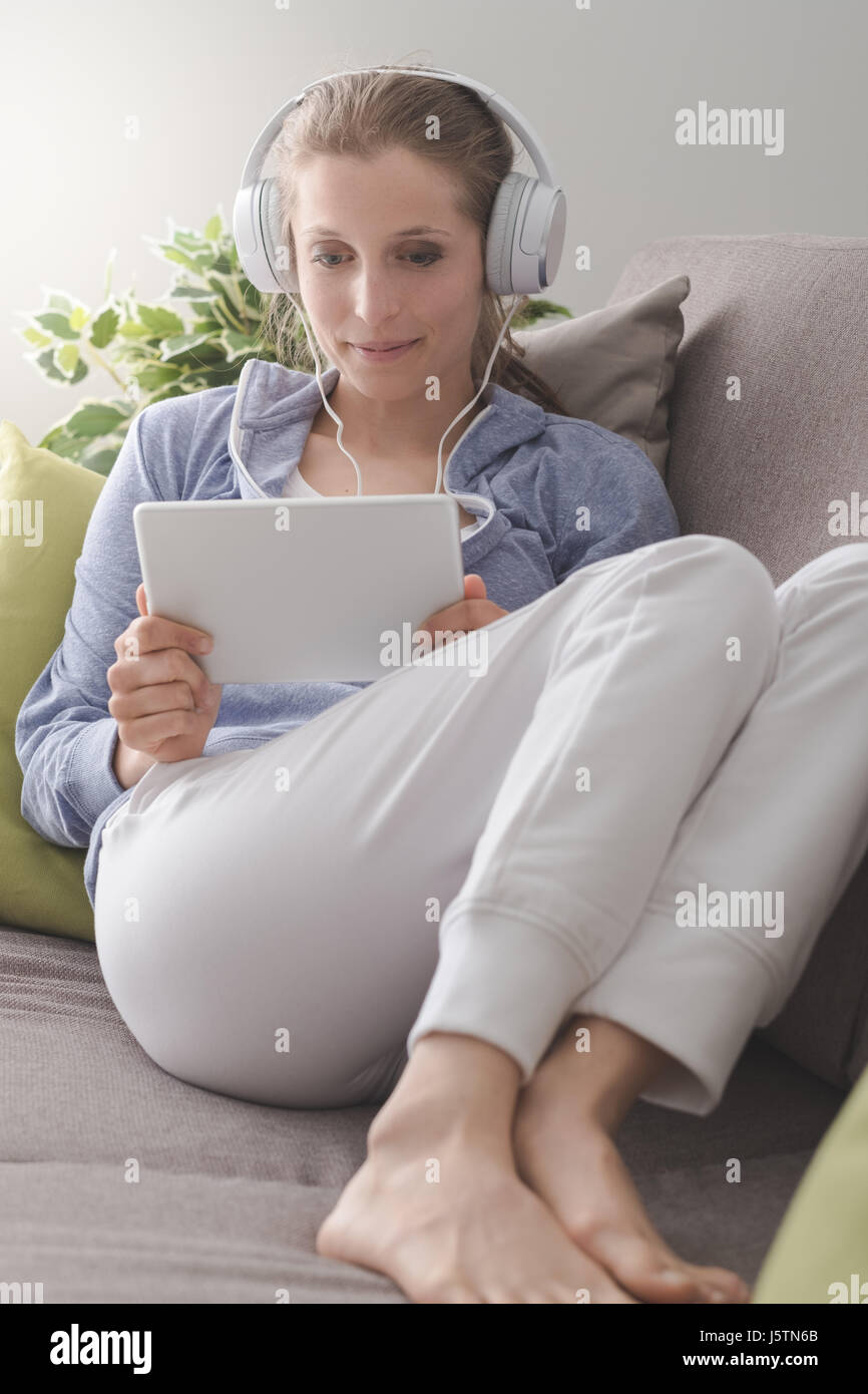 Attraktive Frau zu Hause im Wohnzimmer entspannen, ist sie auf dem Sofa ...